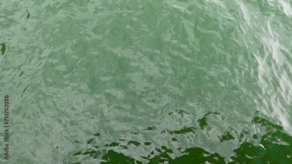 Sunlight and its reflection on small ripples of green river water ...