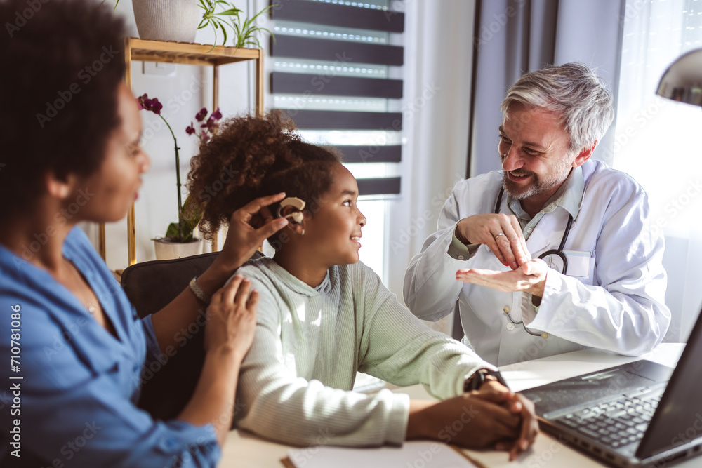 Smiling deaf african american girl with ear implant at doctor's office ...