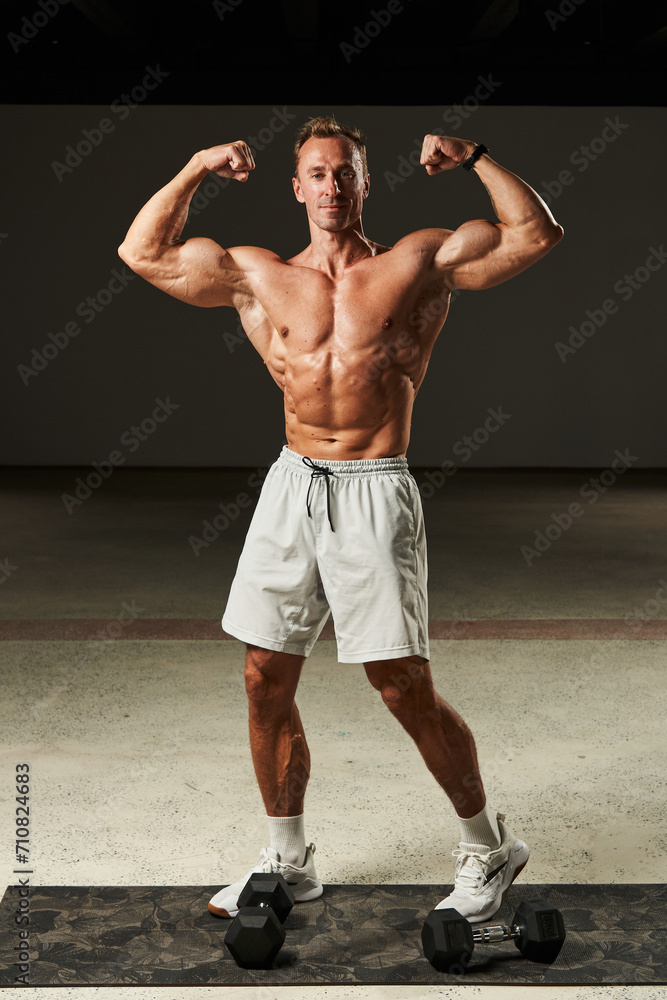 Flexing his chiseled physique and veins bulging, he lifts weights with ...