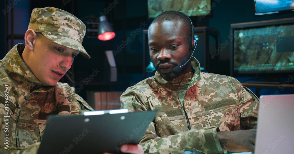African American military dispatcher sitting in office and Caucasian ...