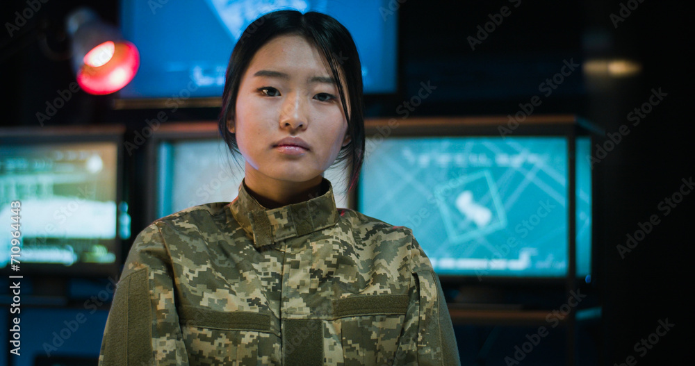 Portrait of pretty Asian female soldier standing in monitoring room and ...