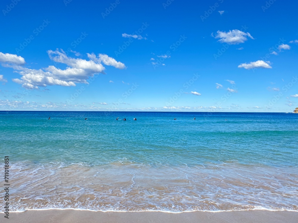 Surfers practicing catching a wave in the turquoise-blue ocean. Surf ...
