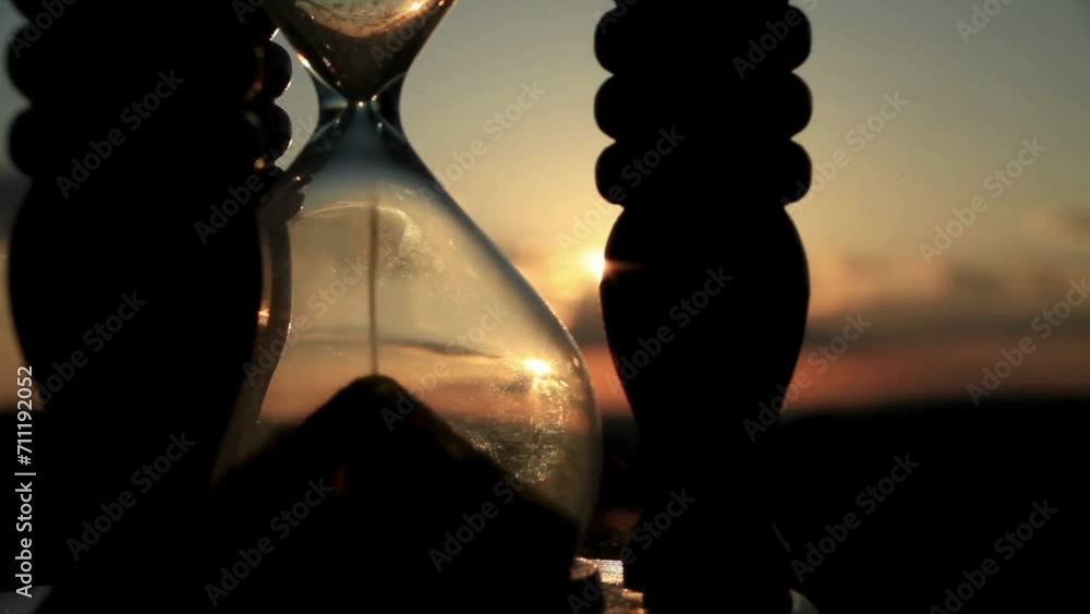 Vidéo Stock An hourglass with spilling sand standing on nature ...