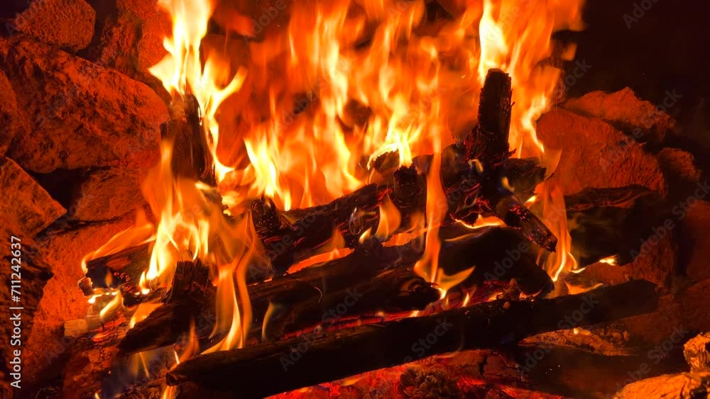 Burning big wooden sticks and logs at a big camp fire, hot flames ...