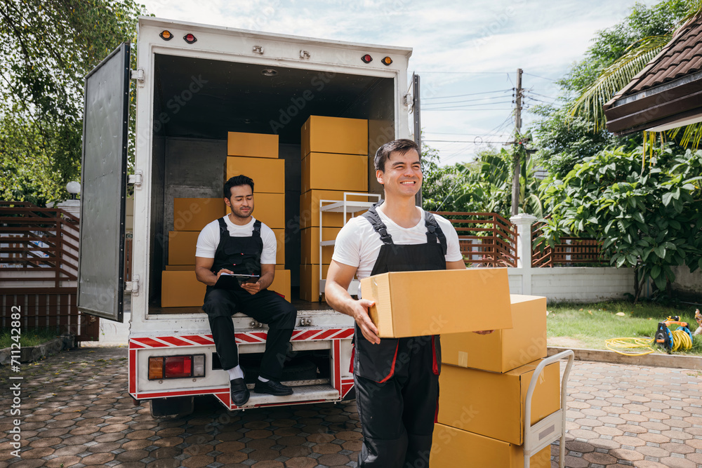 Moving service workers unload boxes from a van showing teamwork and ...