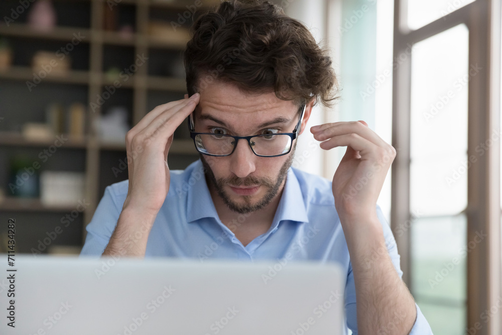 Close up face of young man in glasses stare wide-eyed at laptop screen ...