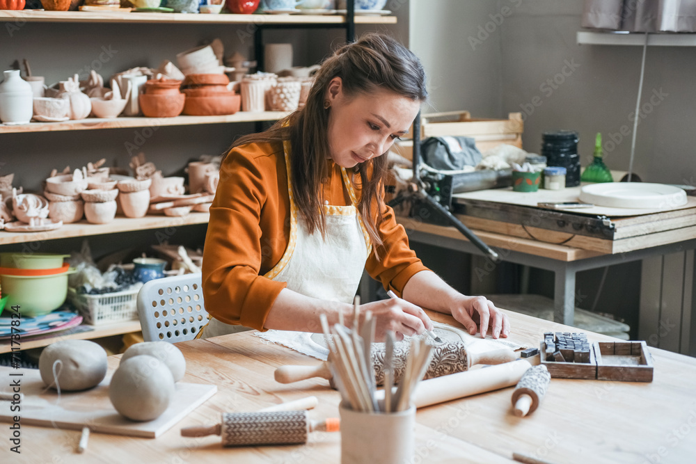 Middle-aged woman moulding a plate in a pottery studio. The potter is ...