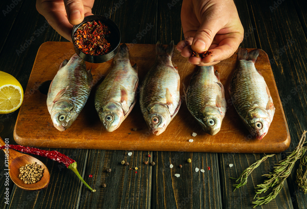 Adding spices to fresh raw fish by the hands of a chef. The process of ...