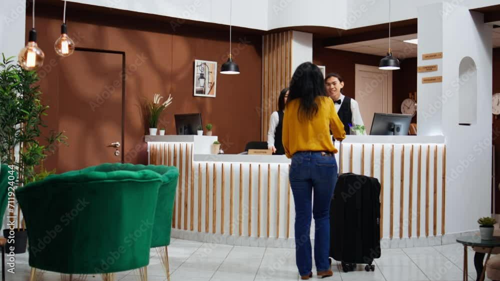 Asian woman approaching front desk in hotel lobby, receptionist asking ...