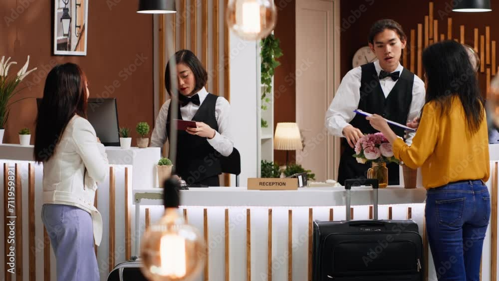 Tourists going through check in process at hotel reception desk, staff ...