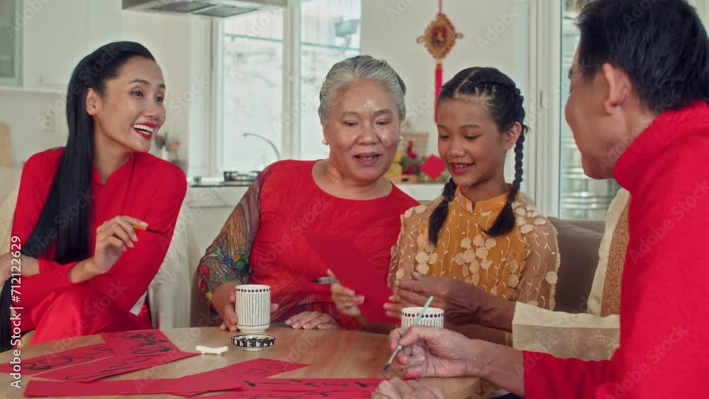 Pan shot of Asian family in national costumes writing calligraphy on ...