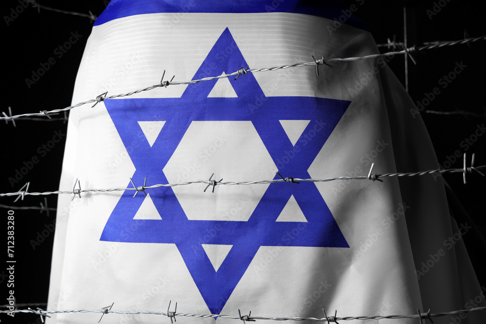 Jewish woman with flag of Israel behind barbed wire on black background ...