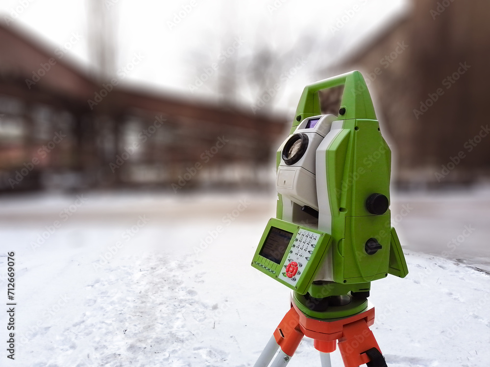 Total station at work on a blurred industrial background. Electronic ...