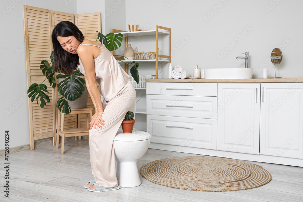 Young Asian Woman With Hemorrhoids And Cactus On Toilet Bowl In
