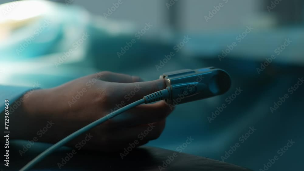 Close-up tracking shot of pulse oximeter on finger of patient during ...