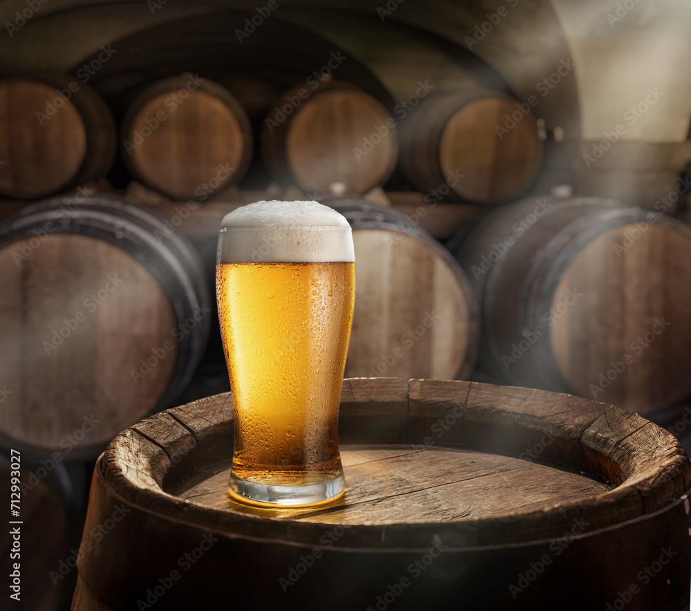 Glass of beer on top of wooden barrel and wood barrels in cellar at the ...