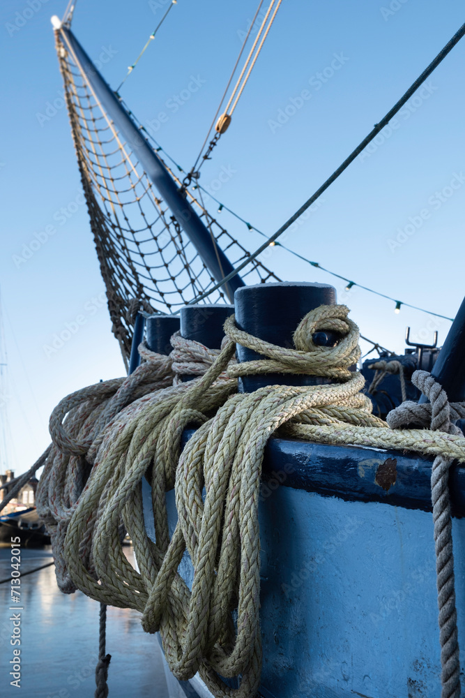 Ship's ropes twisted around the iron bollards on the railing of a metal ...