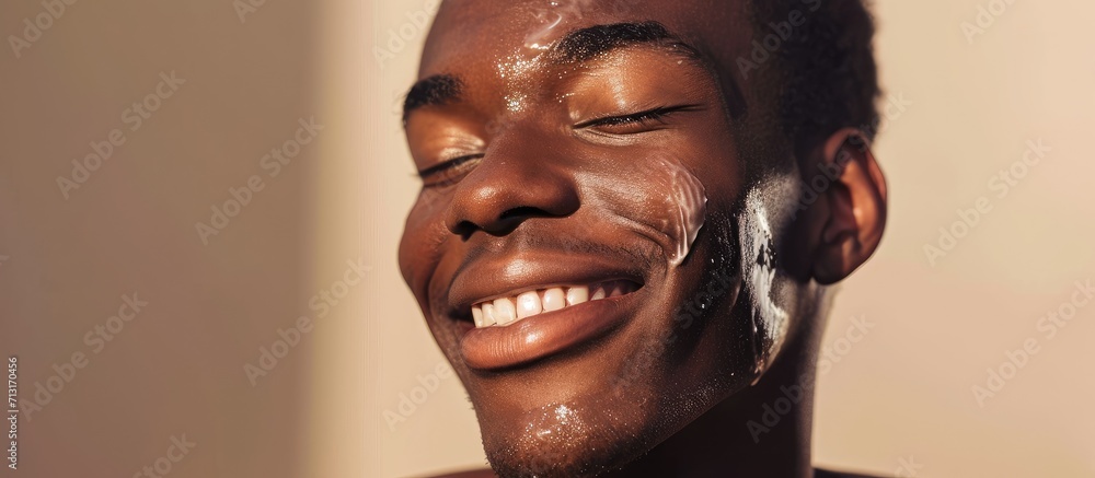 Young black man smiling while applying beauty oil to his melanated face ...