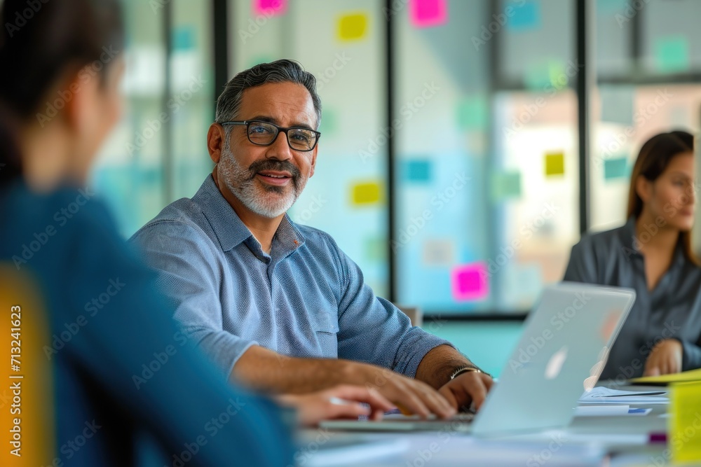 Latino man in his mid 40s confidently leading a team meeting with a ...