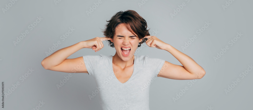 Portrait of young woman covering her ears plugging with fingers and ...