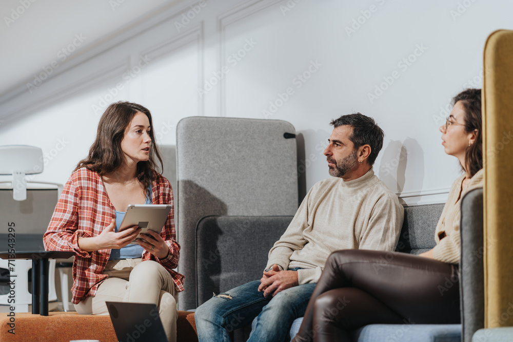 Three professional colleagues discuss work-related matters while seated ...
