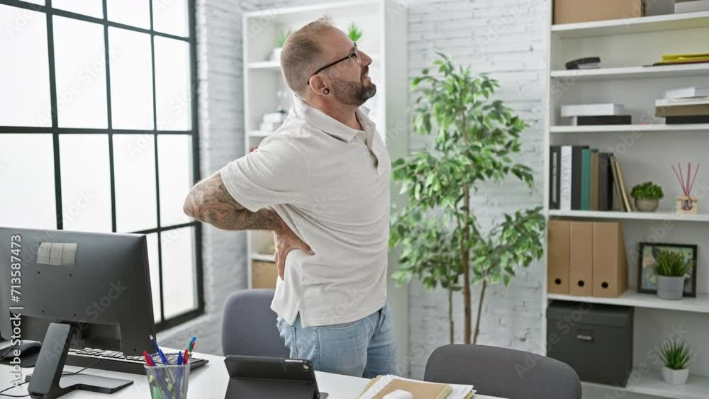 Unhappy young man worker suffering from backache while standing indoors ...