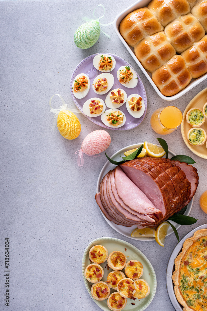 Easter brunch on large table with spiral sliced ham, quiche, deviled ...