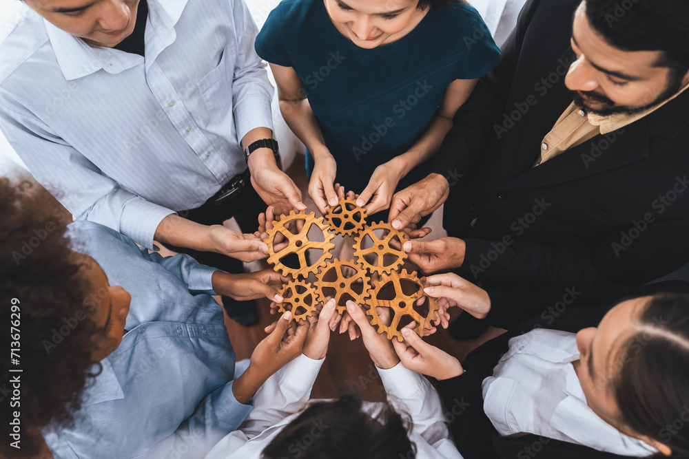 Office worker holding cog wheel as unity and teamwork in corporate ...
