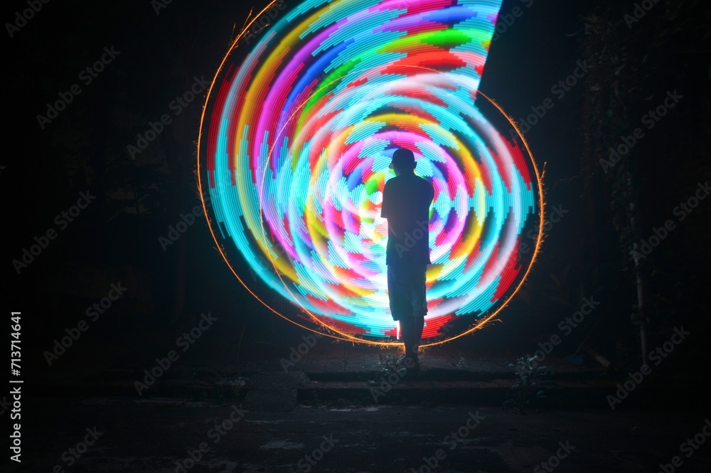 One person standing alone against a Colourful circle light painting as ...