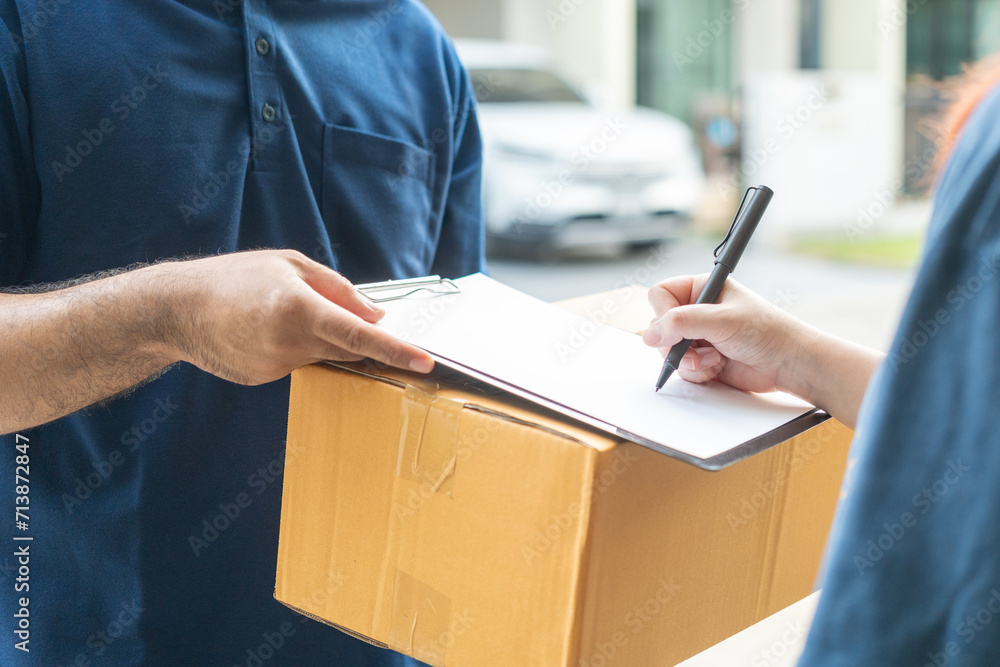 Delivery man holding a cardboard box while woman putting signature in ...