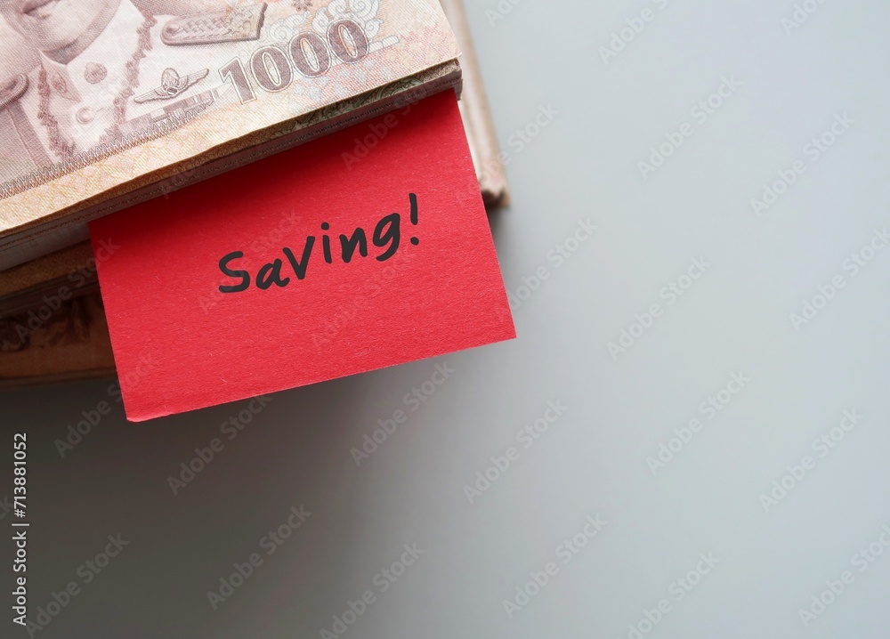 Stack of cash Thai Baht and red note with text written SAVING!, concept ...