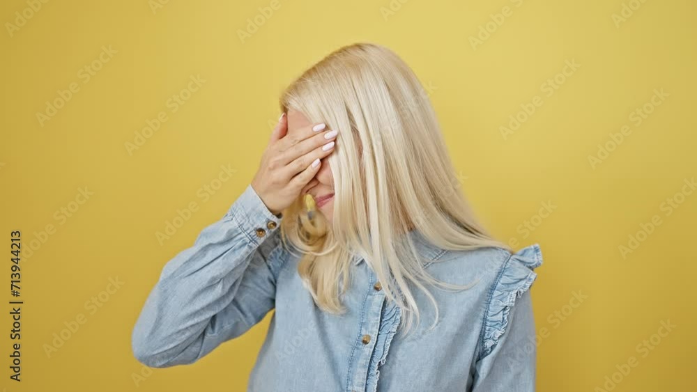 Shocked young blonde woman in denim shirt afraid and timid, peek-a-boo ...