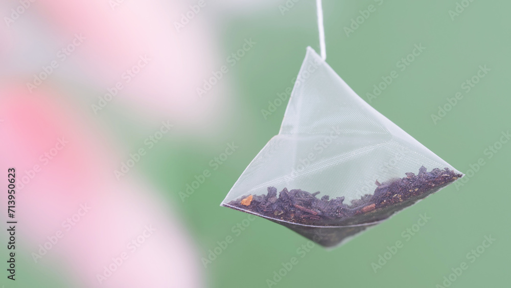 Triangular pyramid tea bag on gradient green-pink defocused background ...