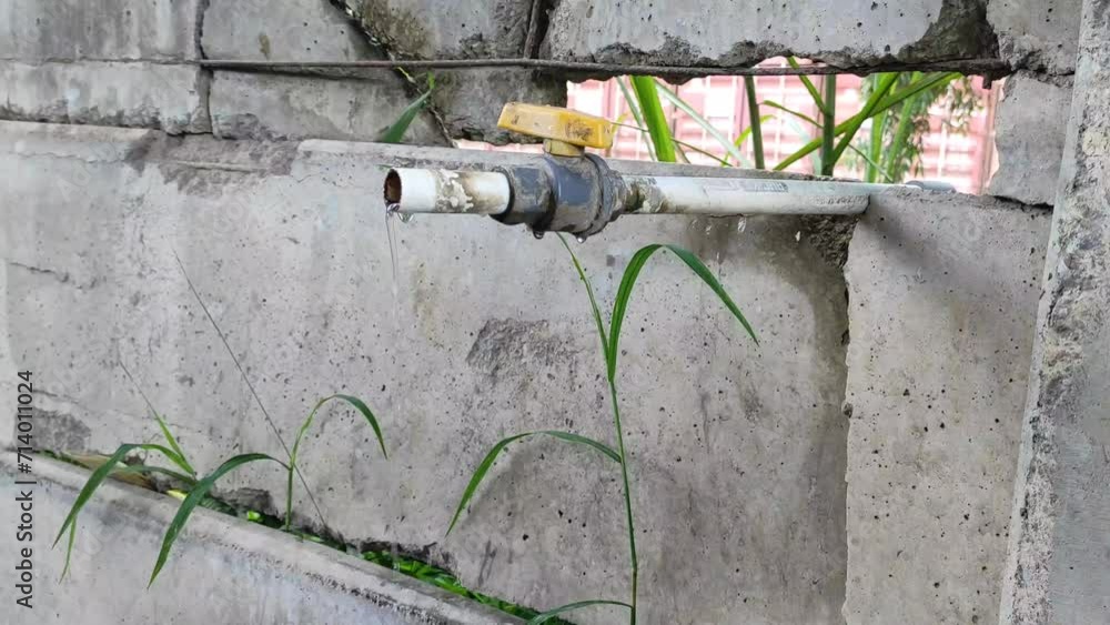 The water tap pipe is leaking, with a hole in the concrete wall. Clean ...