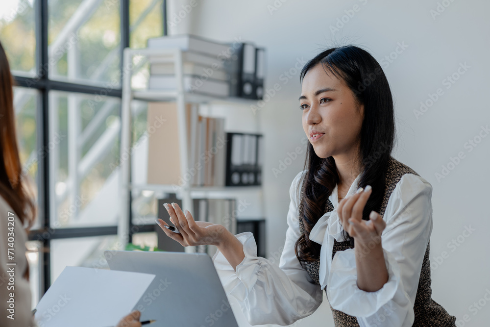 Two beautiful female colleagues interacting while working in office ...