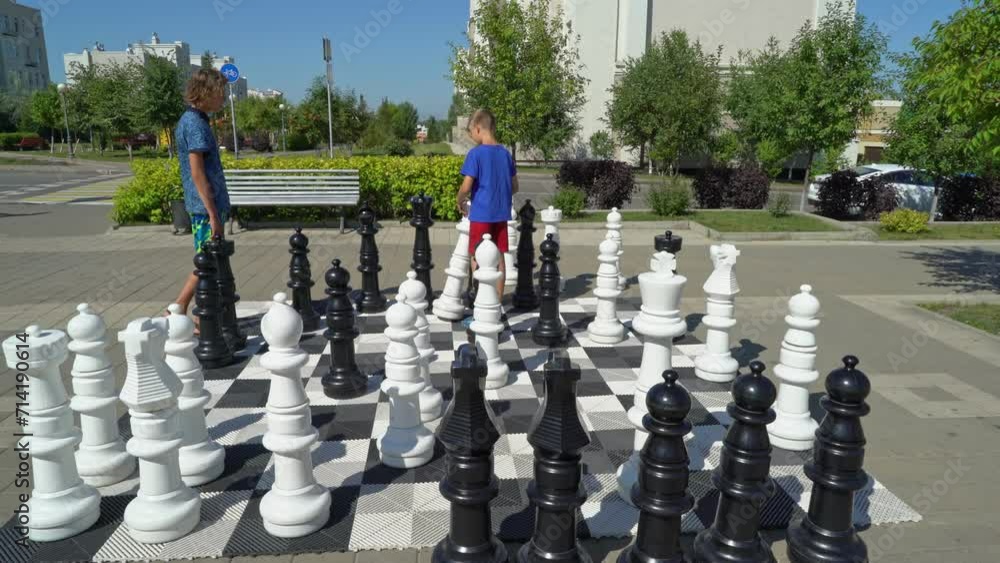 Two boys, playing with giant chess board. A chess game with large chess ...