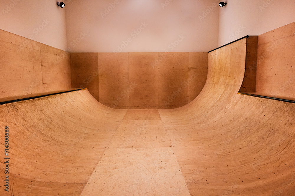 An indoor skateboard sports ramp / halfpipe lit by spotlights with no ...