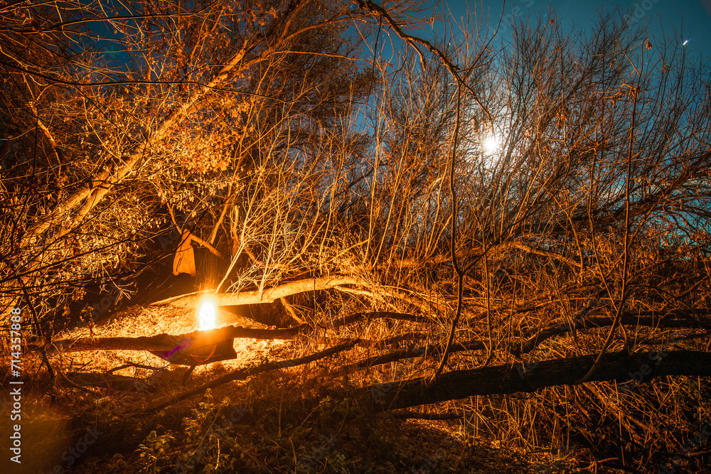 Campfire in the forest, with a hiking jacket hanging behind it and ...