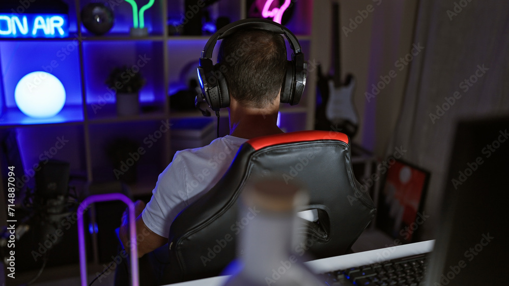 Handsome middle aged man gamer streams late into the night, seated in ...