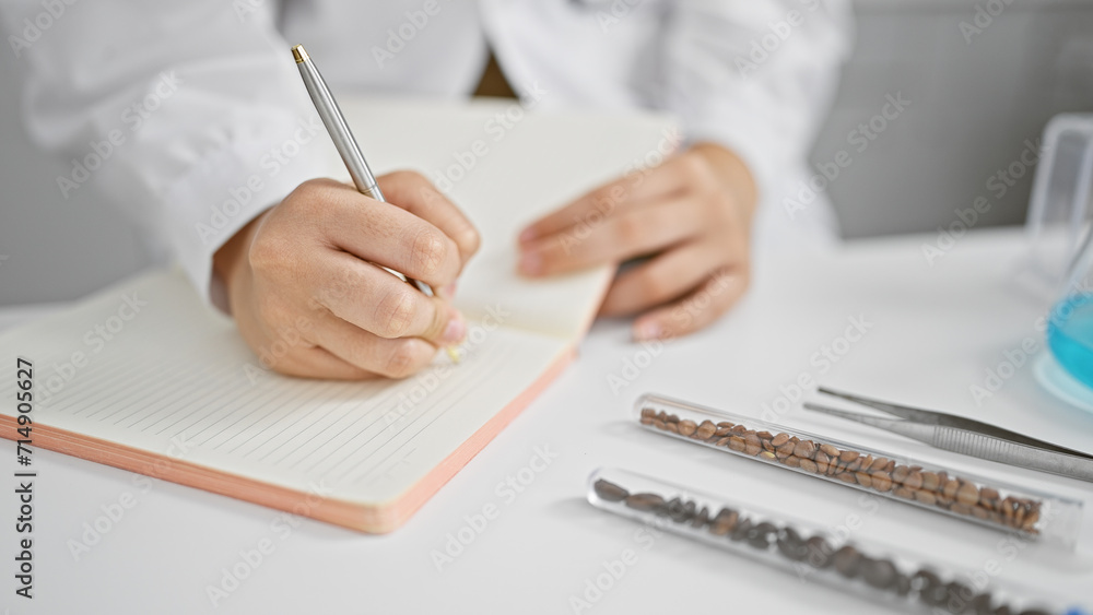 Dedicated hispanic woman scientist engrossed in study, scribbling notes ...