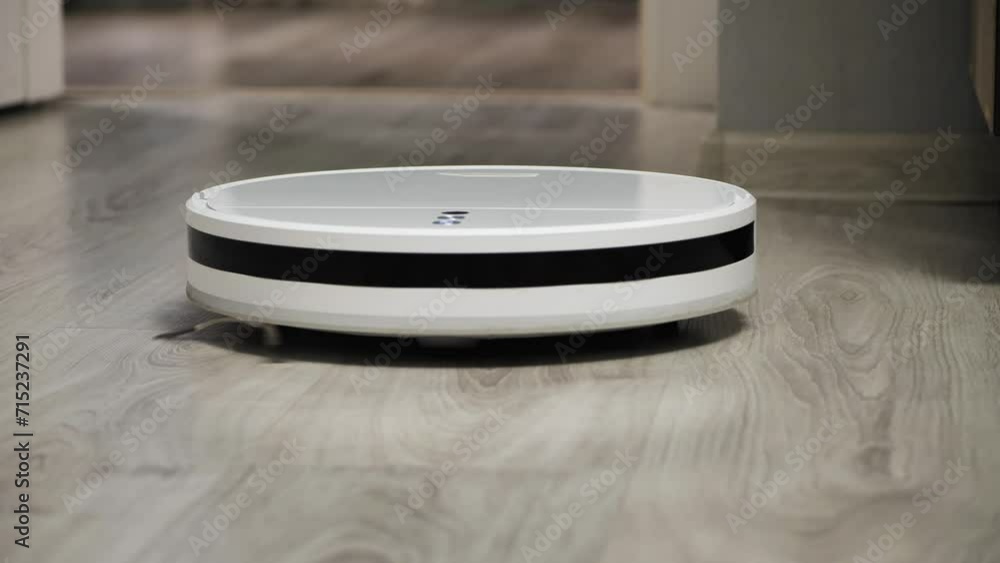 Vidéo Stock Close-up of a white robot hoover vacuuming a wooden floor ...