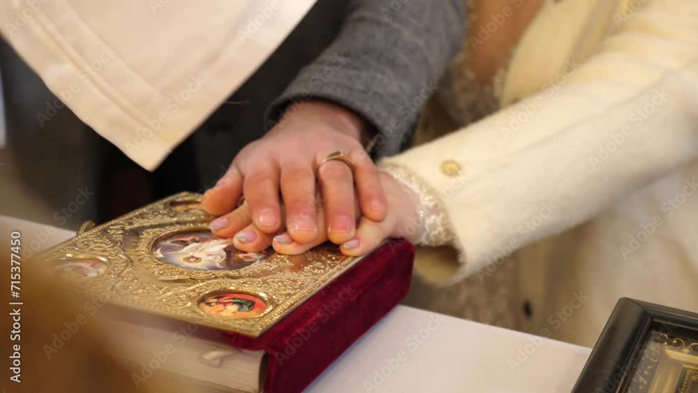 While saying the church vow, the bride and groom put their hands on the ...