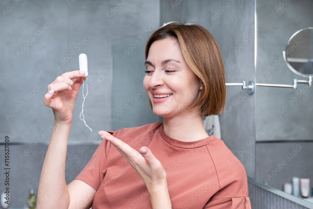 In the bathroom, a woman wears a surprised and happy expression while ...