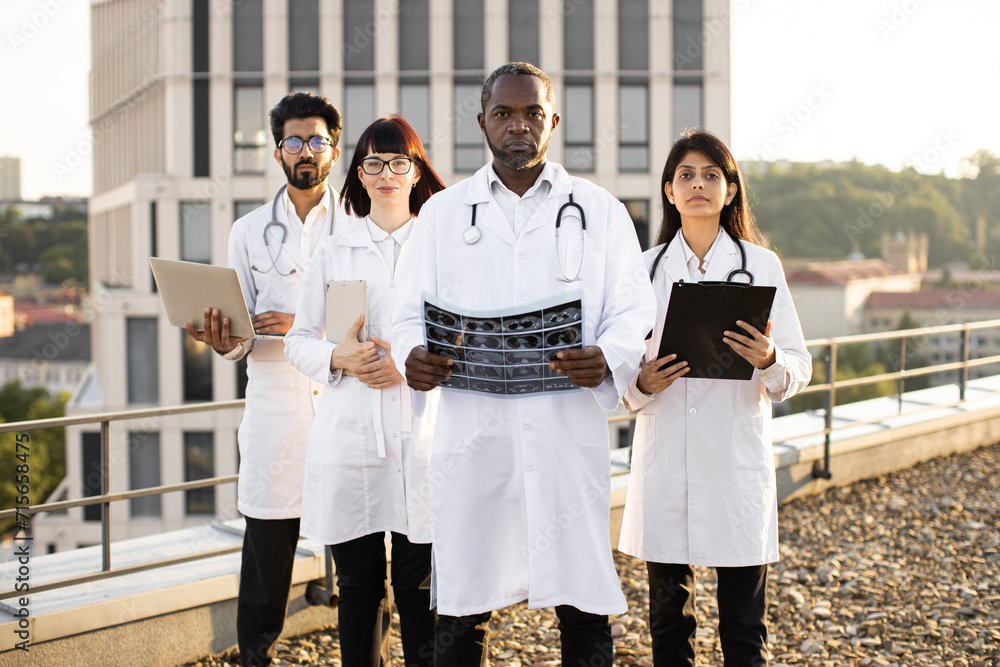 Potrait of multinational medical workers using gadgets while examining ...