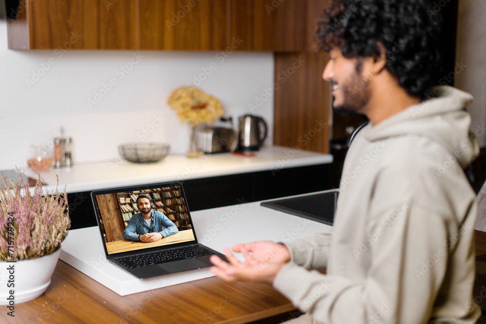 Curly Indian man is having a one-on-one video conversation, talking ...