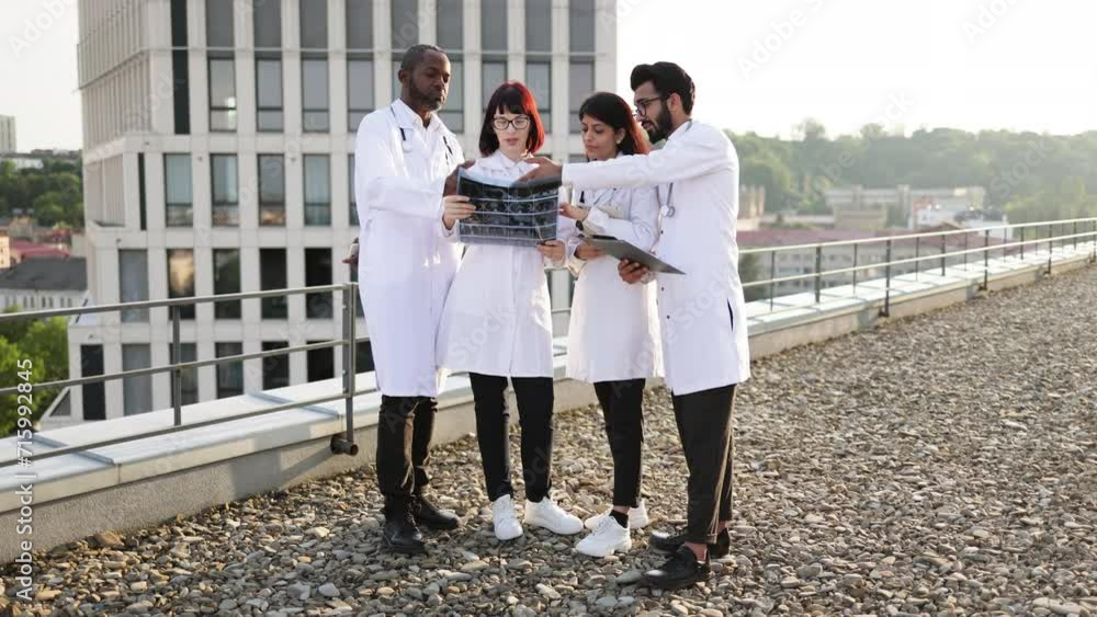 Team of four professional male and female multiracial doctors examining ...