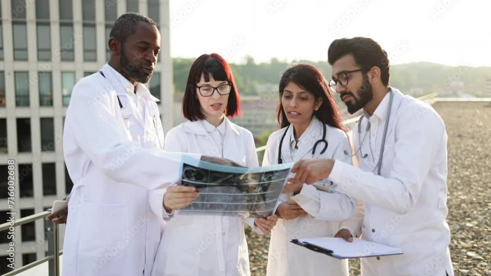 Team of four professional male and female multiracial doctors examining ...