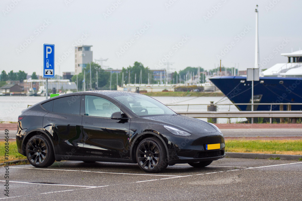 Tesla Model Y charging in a parking lot next to a port in Vlissingen ...