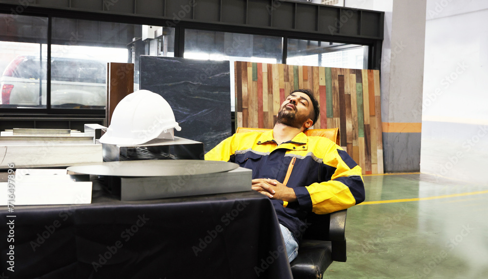 Poster Male hispanic worker takes off his helmet and lies chair with ...