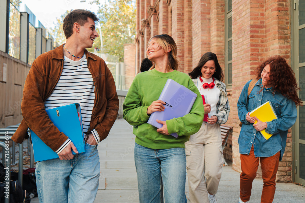 On foreground a couple of teenage students walking and having a ...